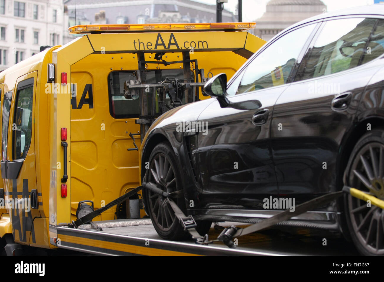 An AA rescue truck carrying a car along a road in London, England Stock ...