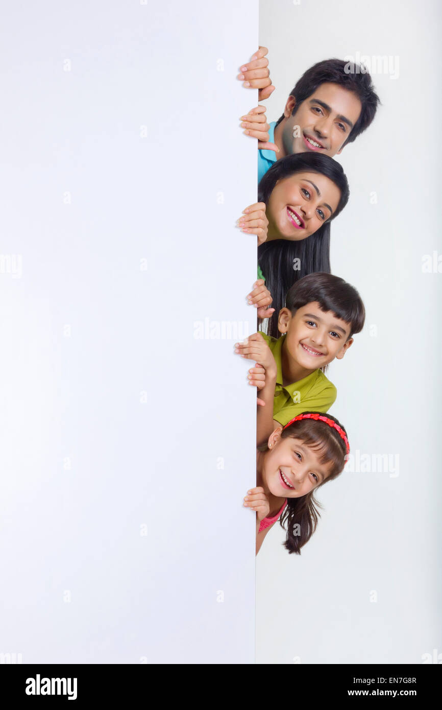 Portrait of family peeking behind white board Stock Photo - Alamy