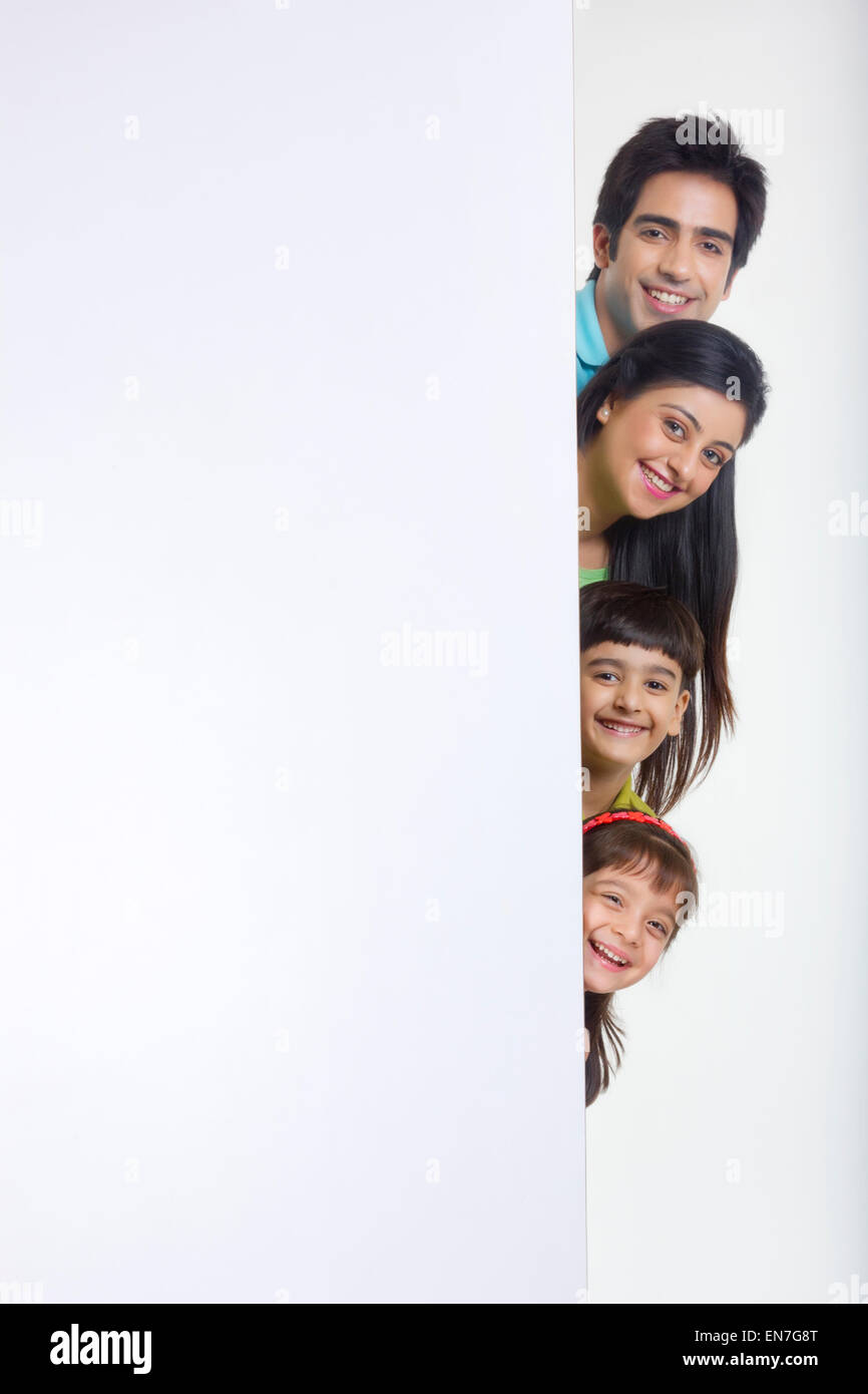Portrait of family peeking behind white board Stock Photo - Alamy