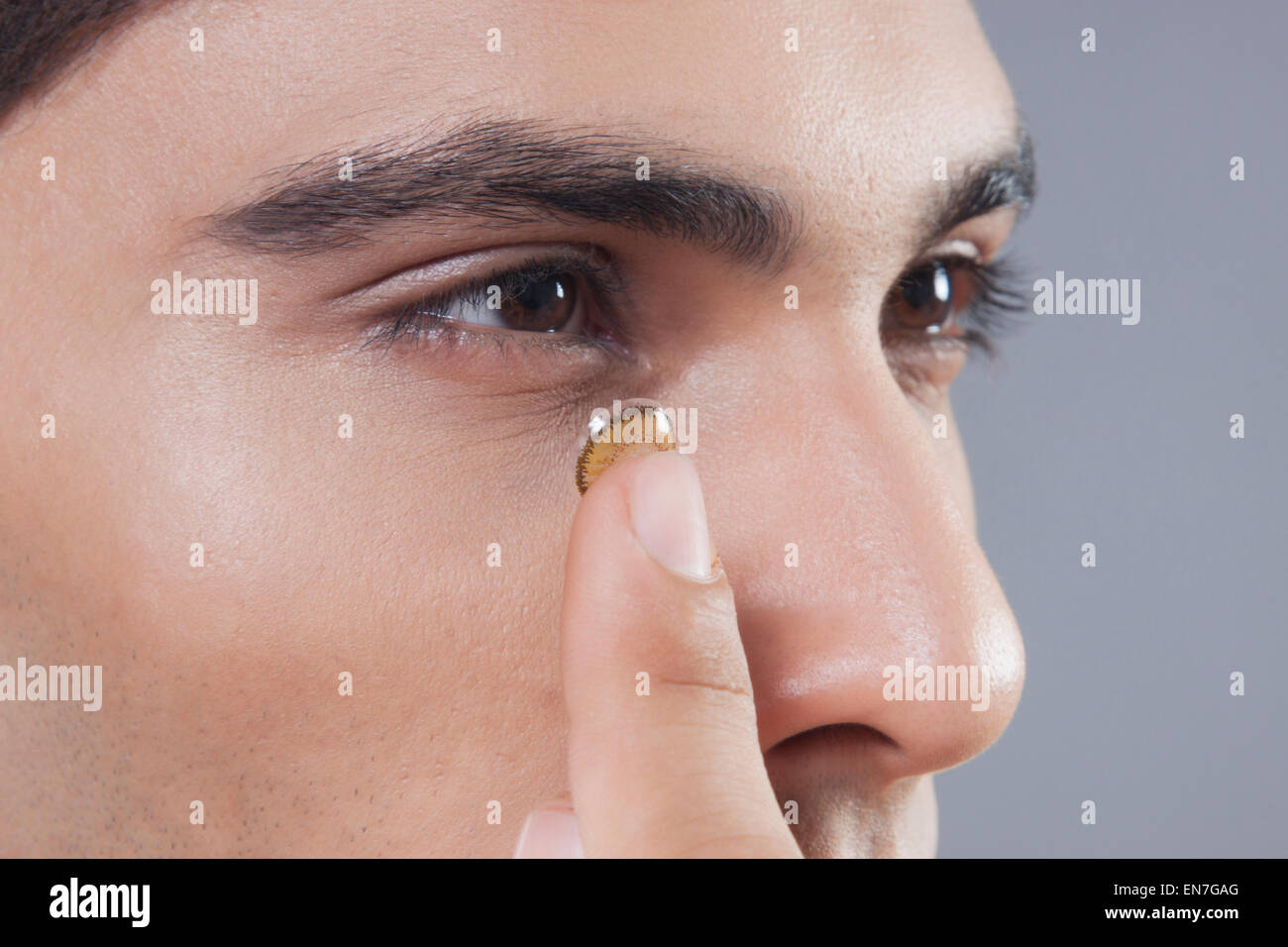 Young man putting contact lens Stock Photo - Alamy