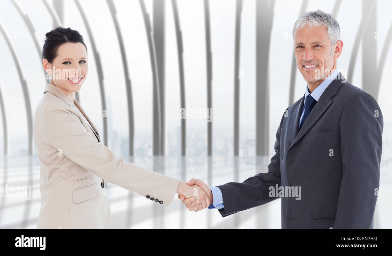 Composite image of smiling business people shaking hands while looking ...