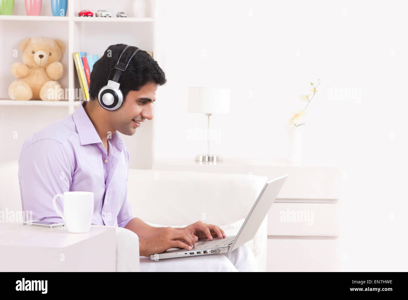 Man listening to music while working on laptop Stock Photo - Alamy