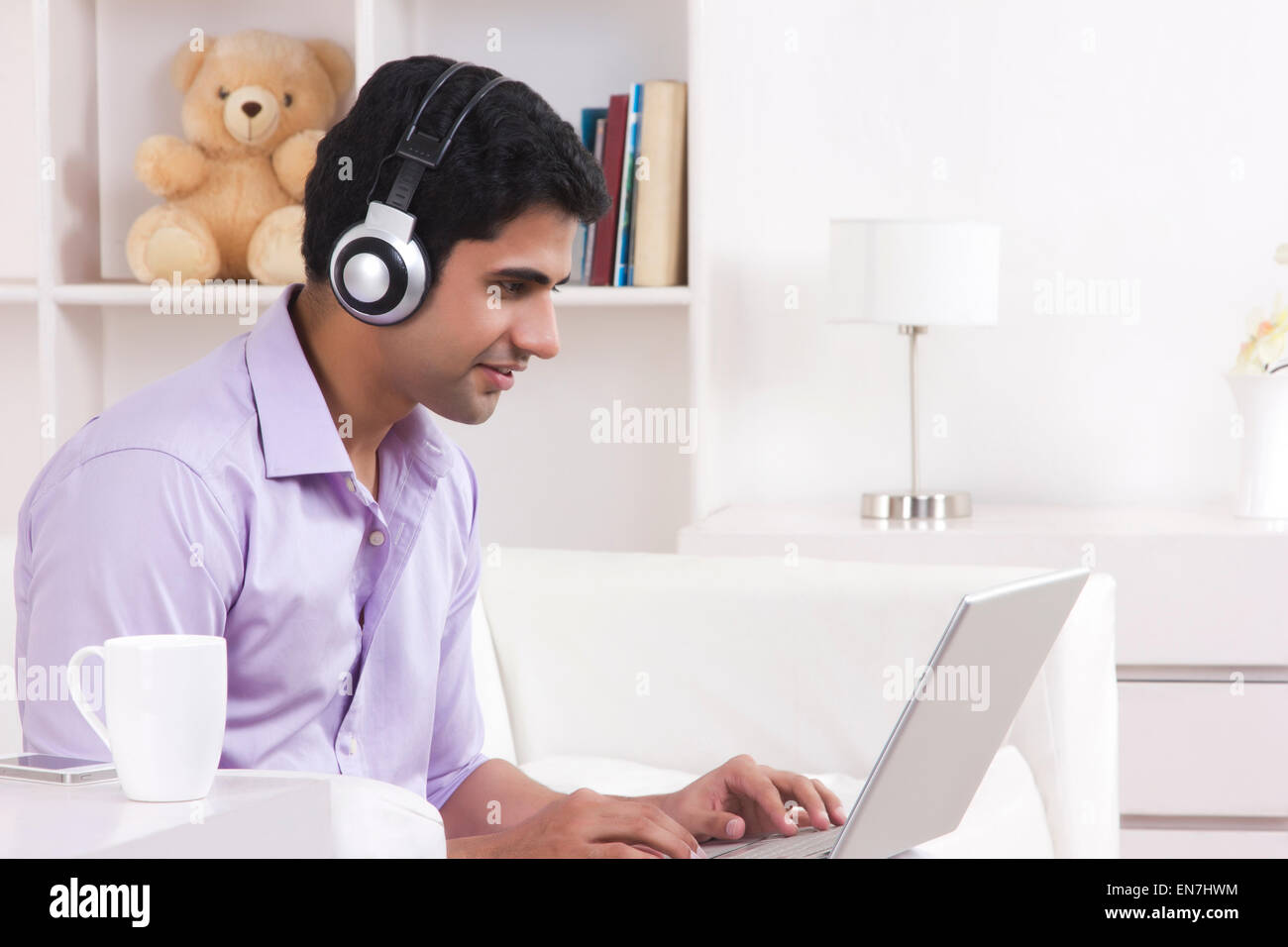 Man listening to music while working on laptop Stock Photo - Alamy