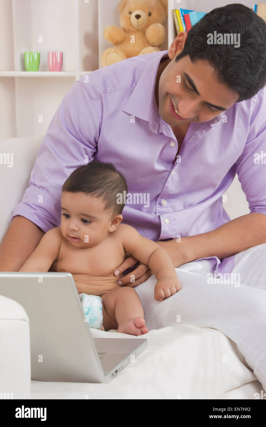 Man with baby and laptop Stock Photo - Alamy