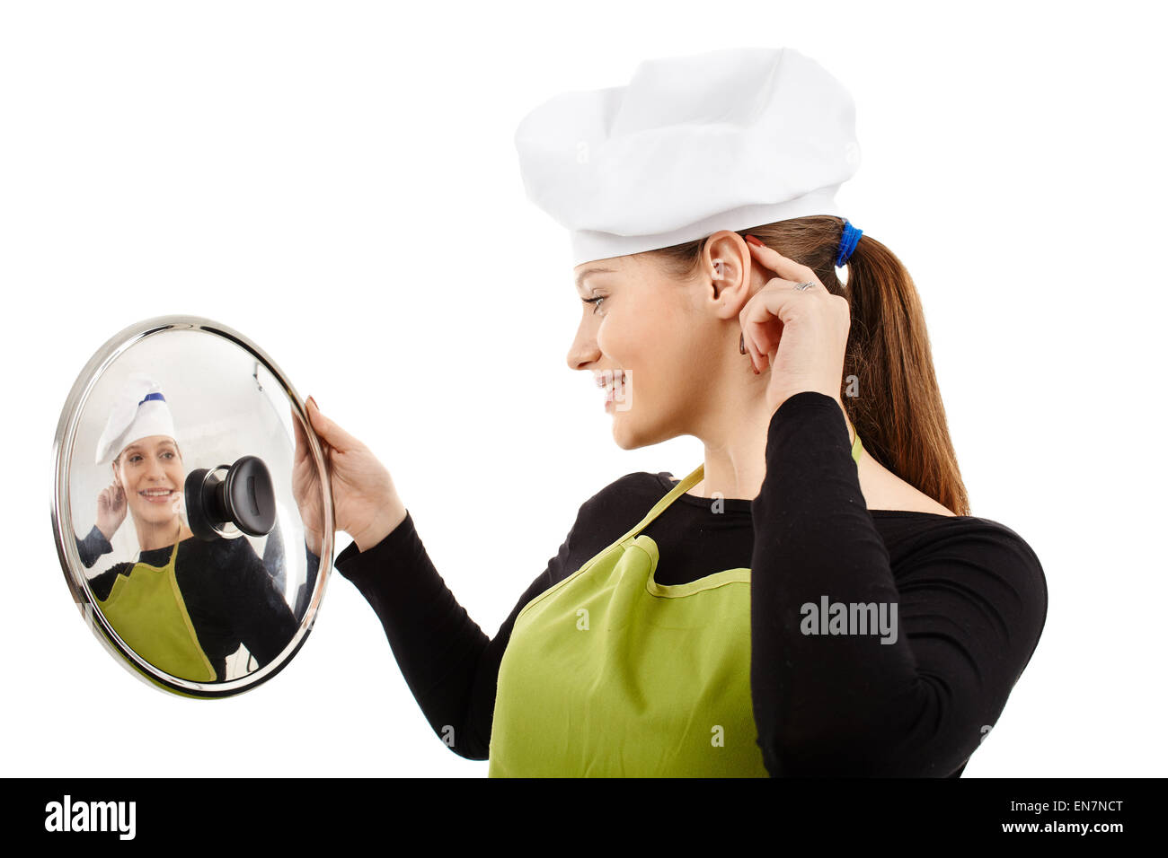 Beautiful young woman cook looking at her reflection in a stainless ...