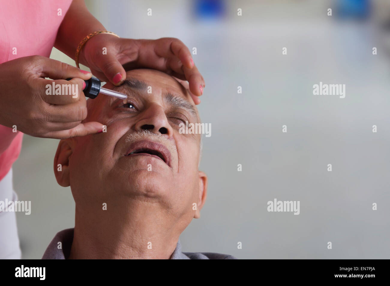 Old man getting eye drops put in Stock Photo - Alamy