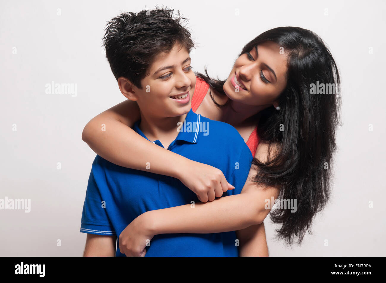 Portrait Of Sister With Arms Around Her Brother Looking At Each Other