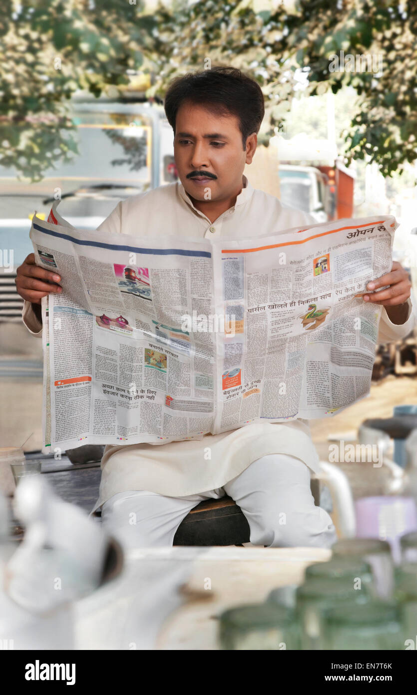 Man reading a newspaper at tea stall Stock Photo - Alamy