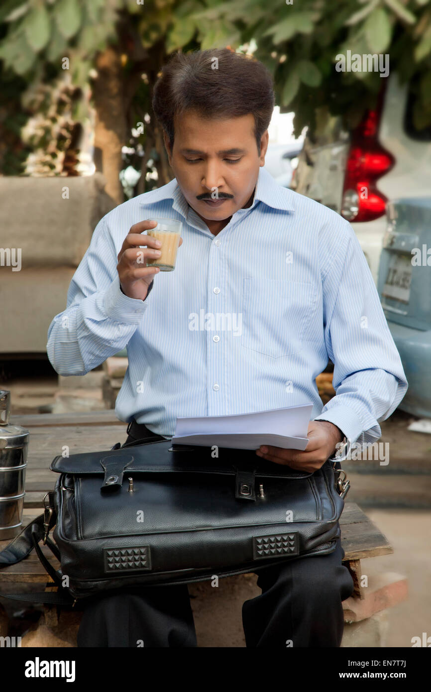 Salesman examining his paperwork and drinking tea Stock Photo - Alamy