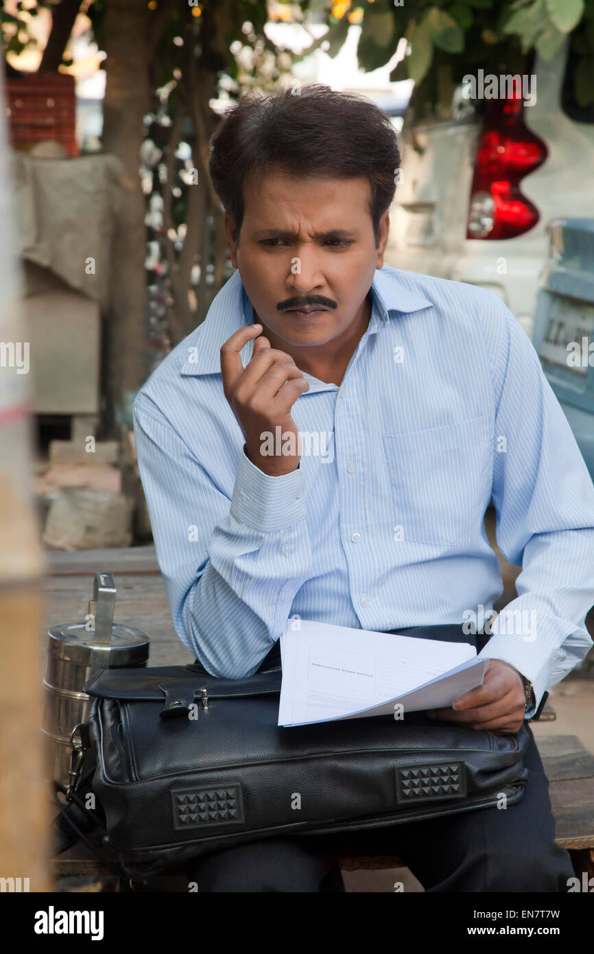 Salesman thinking holding paper work Stock Photo - Alamy