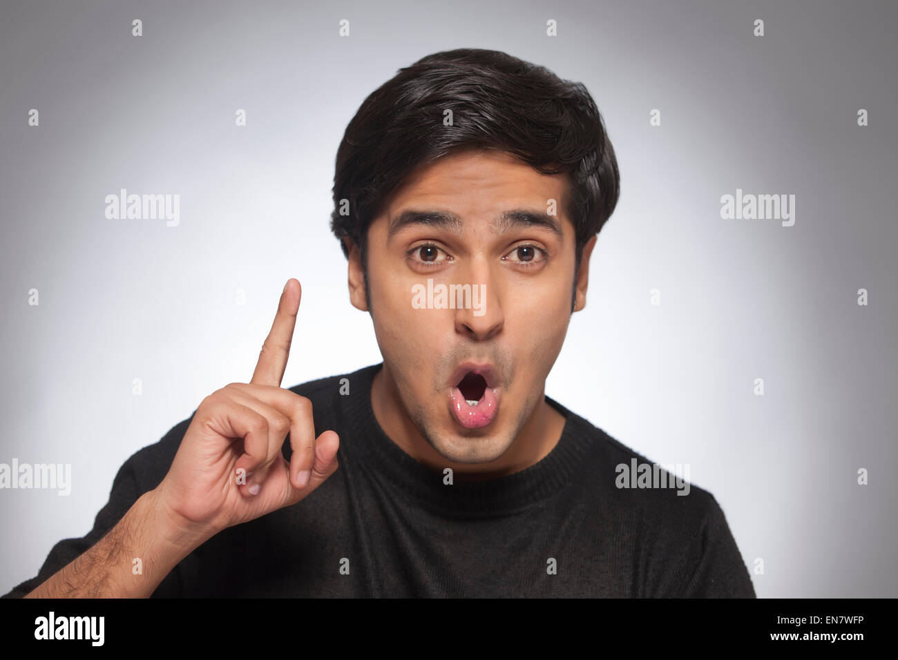 Portrait of a young man raises his finger to make a point Stock Photo ...