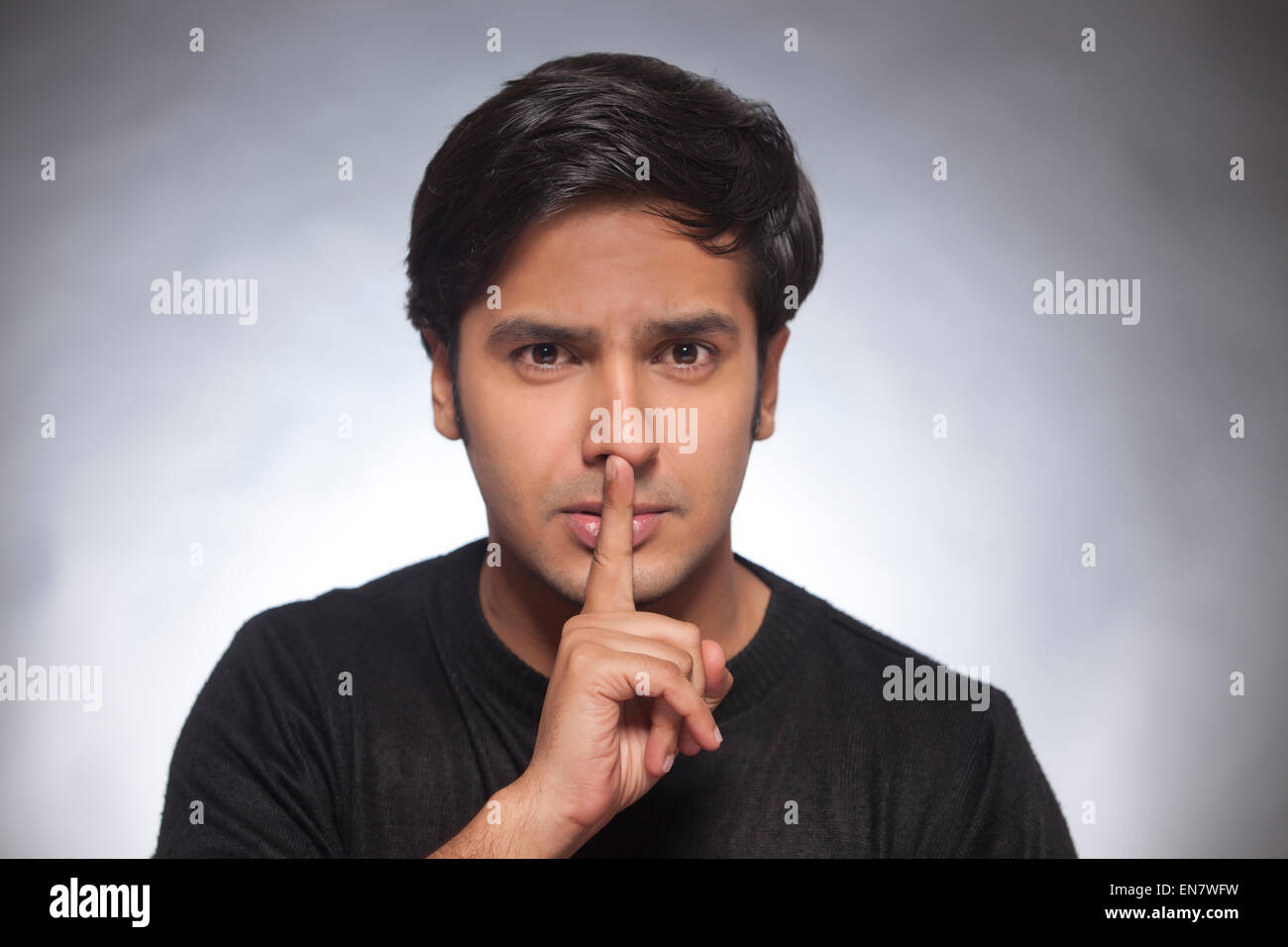 Portrait of a young man with his finger on lips Stock Photo - Alamy