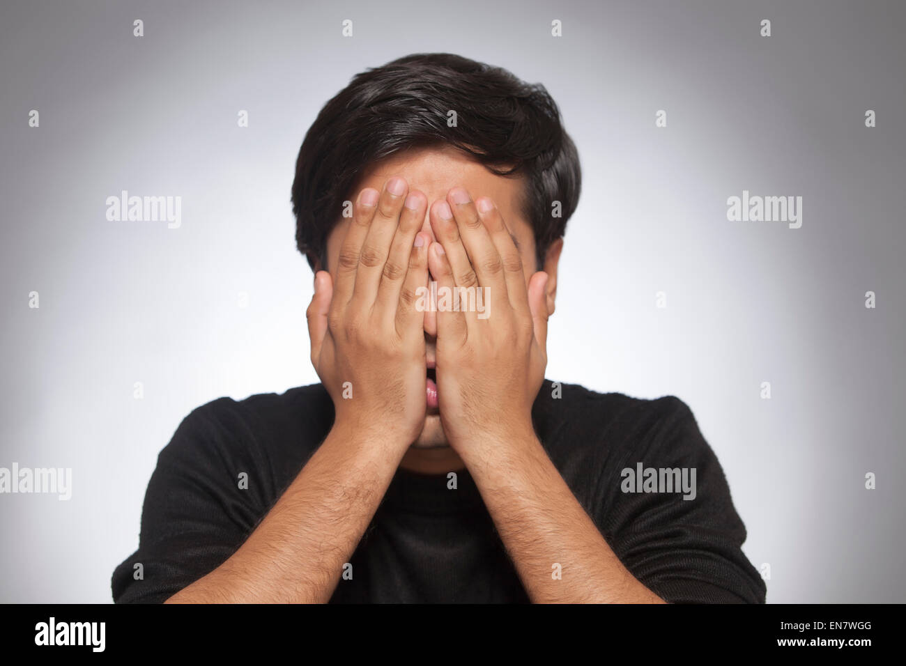 Portrait of a young man with hands covering face Stock Photo - Alamy
