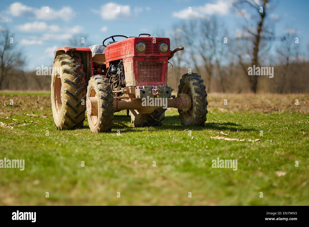 Old dirty tractor on a field with blue sky on background Stock Photo ...