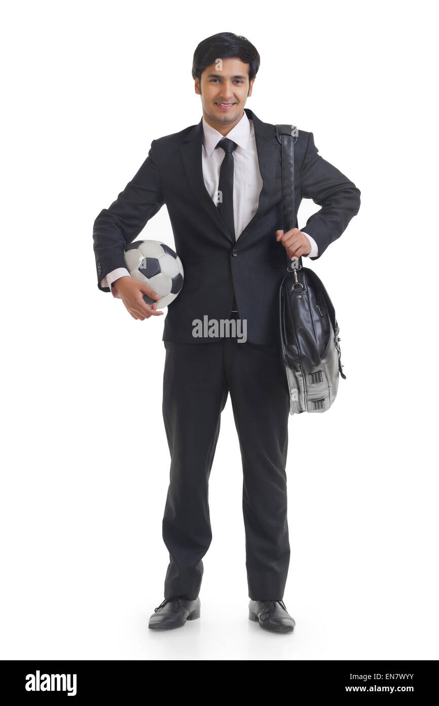 Portrait of smiling businessman holding football and carrying hand bag ...