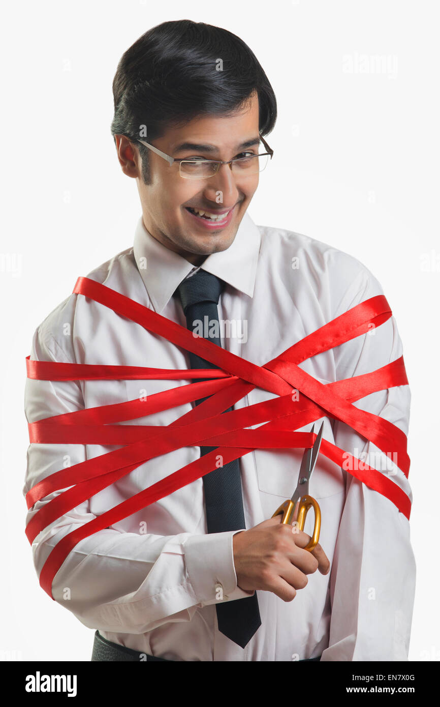 Businessman cutting his wrapped red ribbon Stock Photo - Alamy