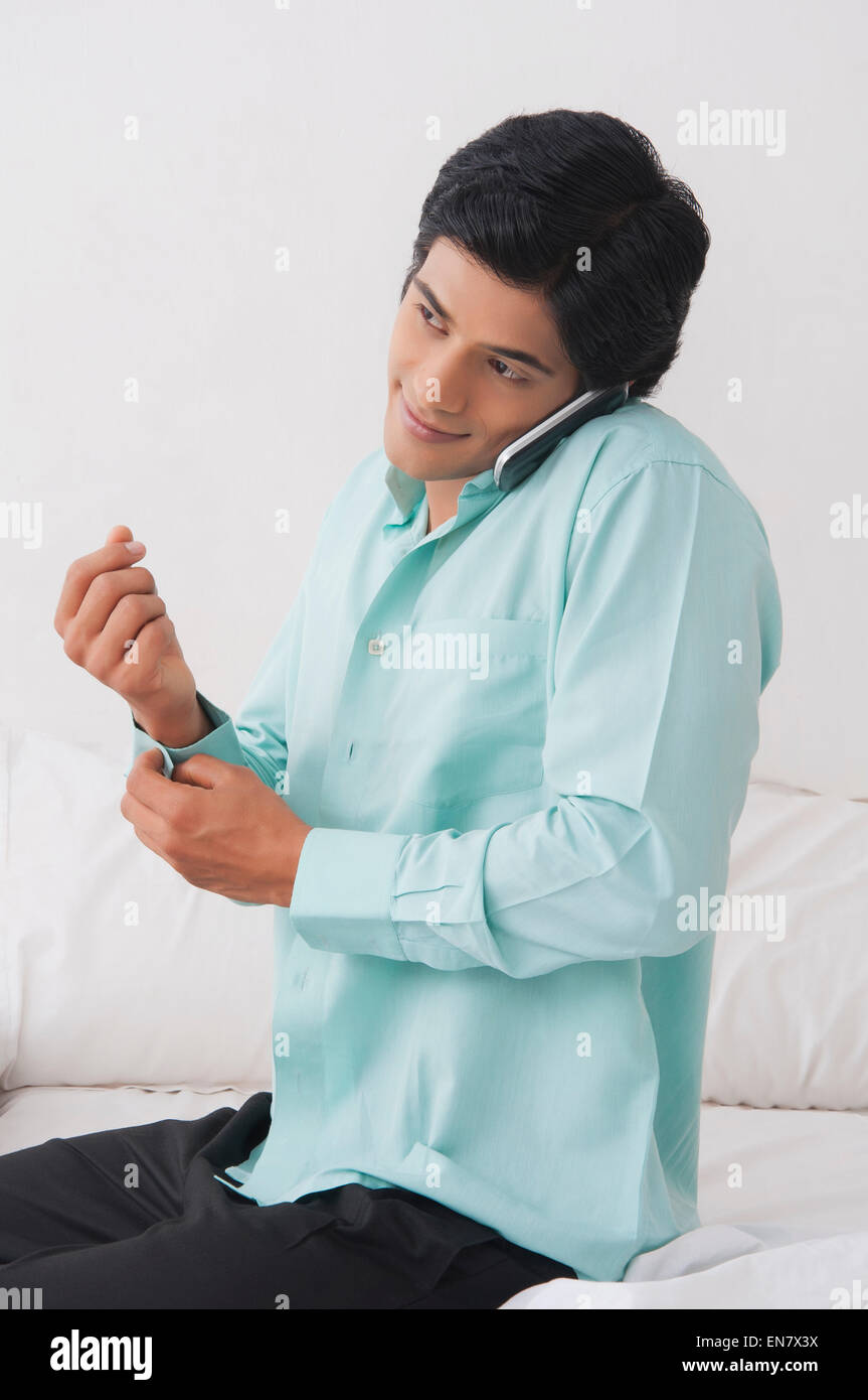 Young man dressing while talking on mobile phone Stock Photo - Alamy