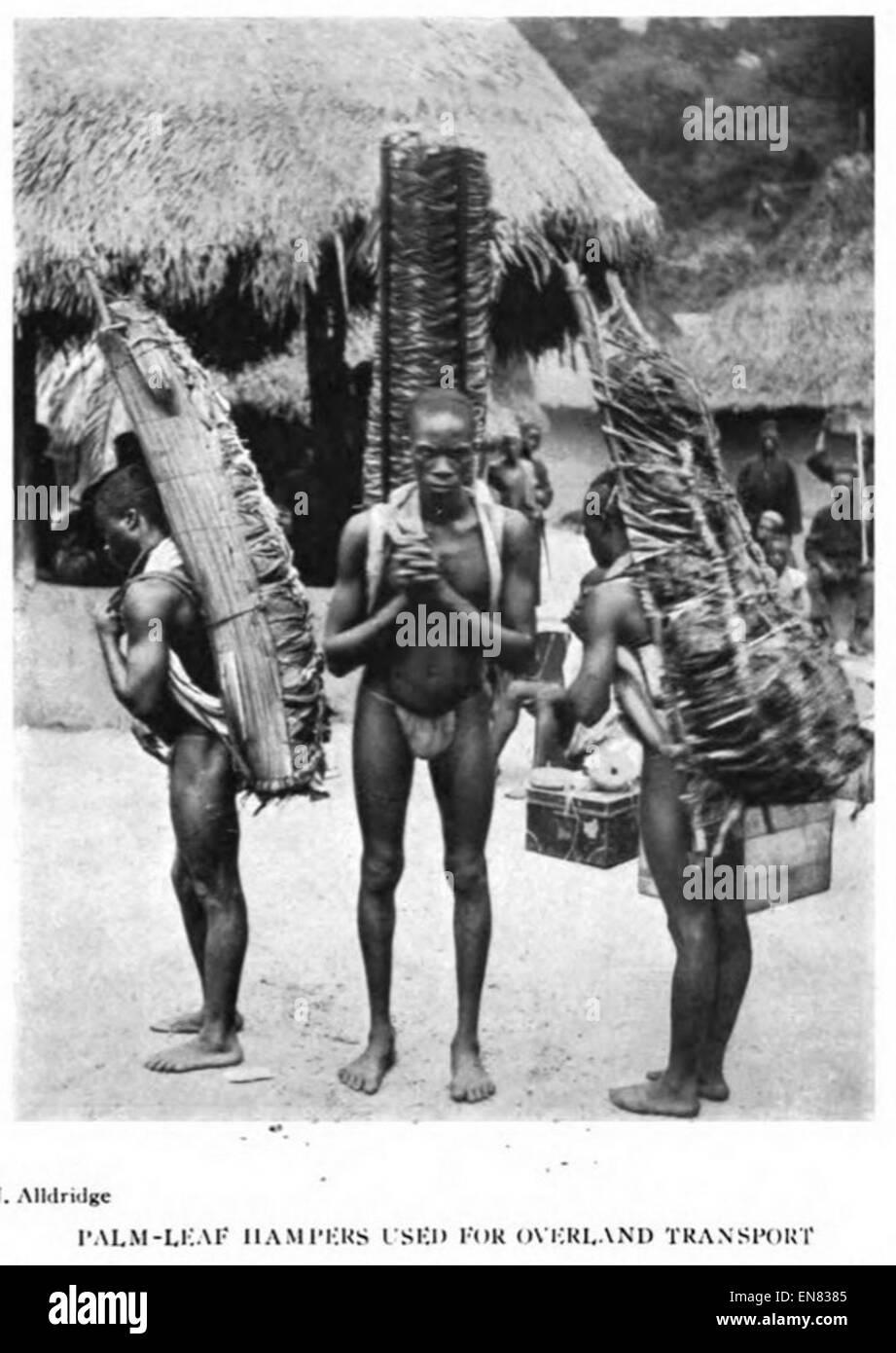 This 1922 photograph shows a group of native carriers in a tropical ...