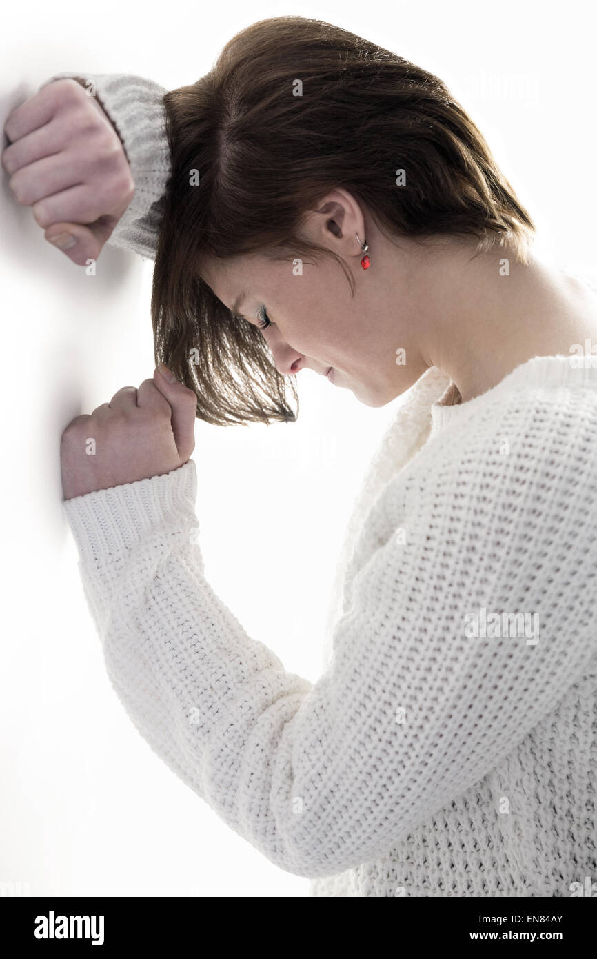 Sad pretty brunette leaning against wall Stock Photo - Alamy