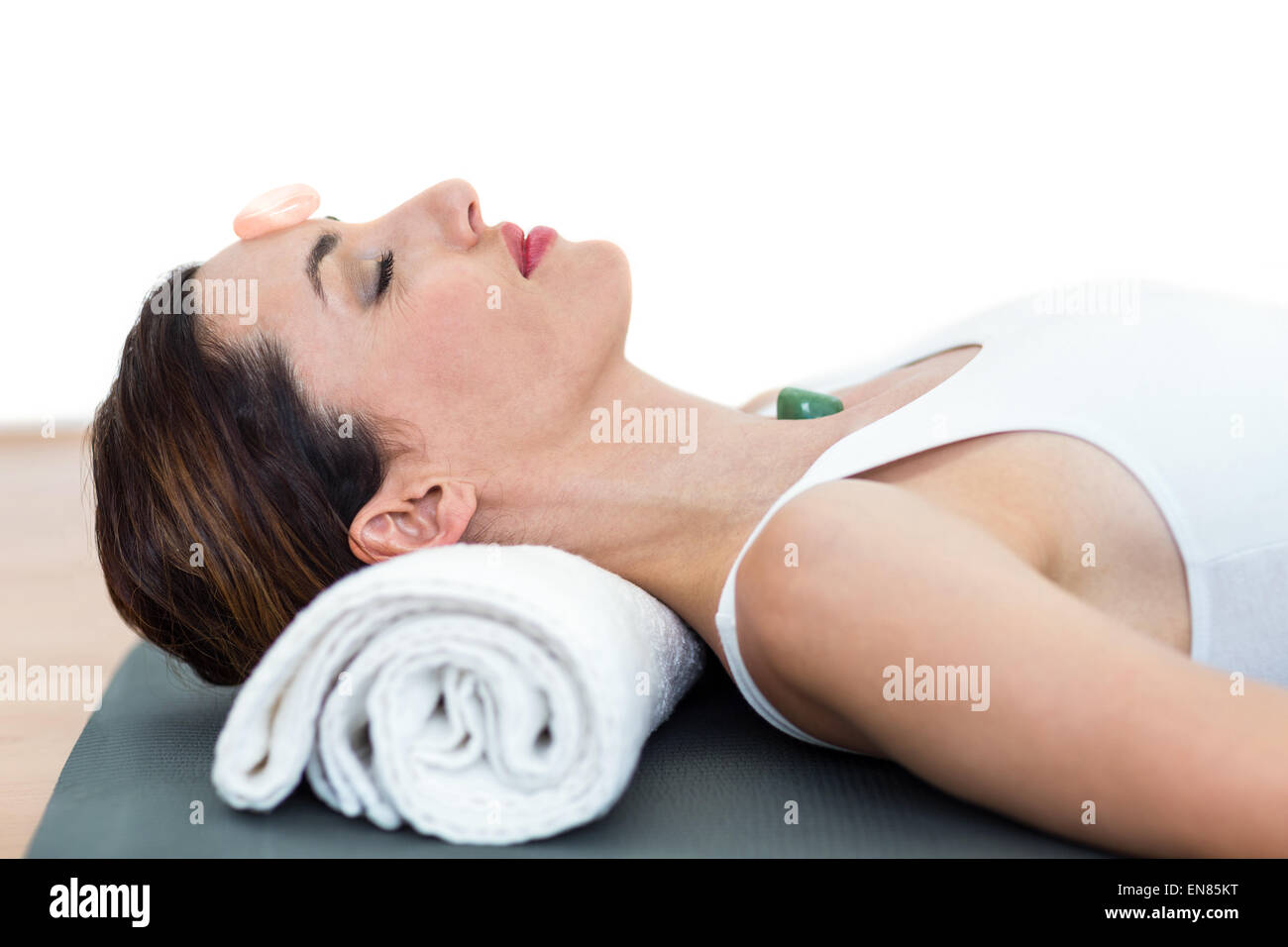 Relaxed brunette lying on mat with stones Stock Photo - Alamy