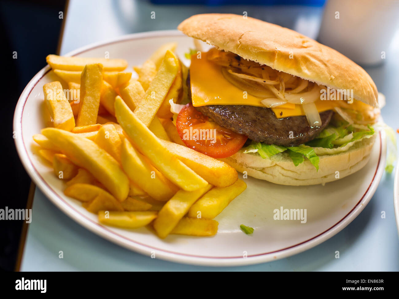 A cheeseburger and chips on a plate and served in a cafe in the UK ...