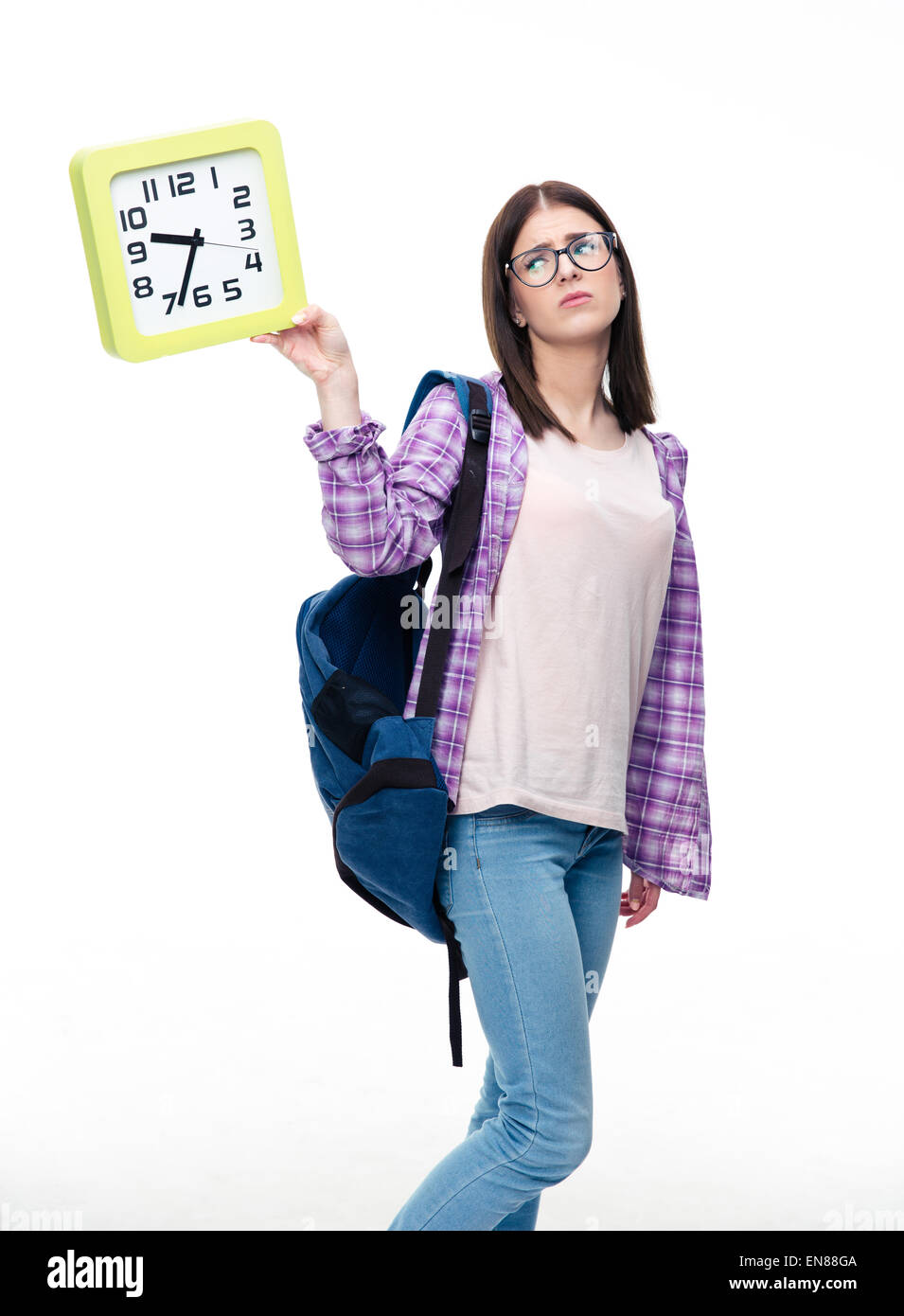 Sad female student with backpack looking at big clock over white ...