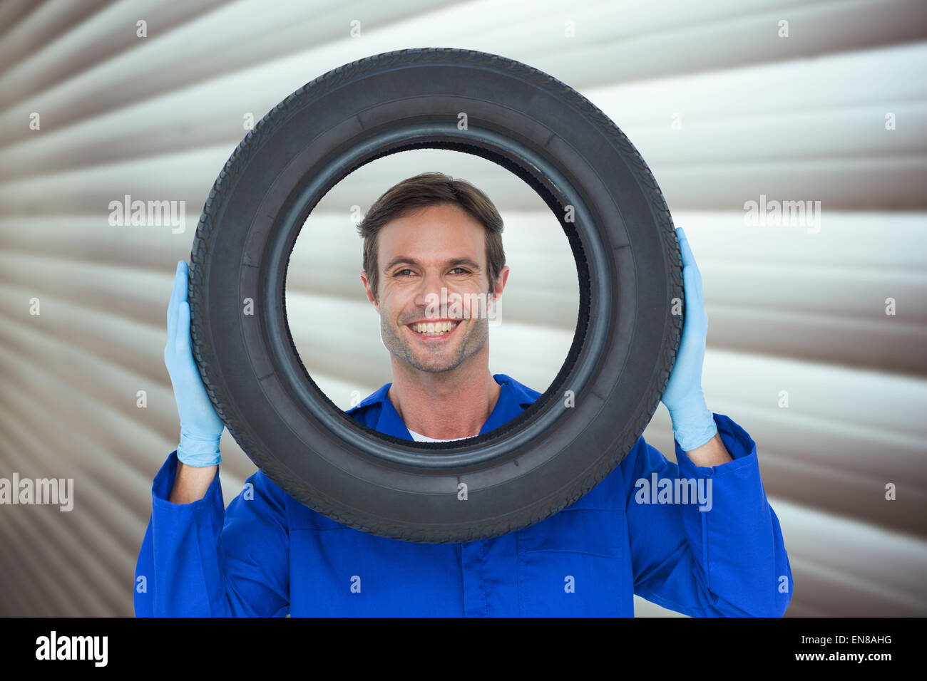 Composite image of confident mechanic looking through tire Stock Photo ...
