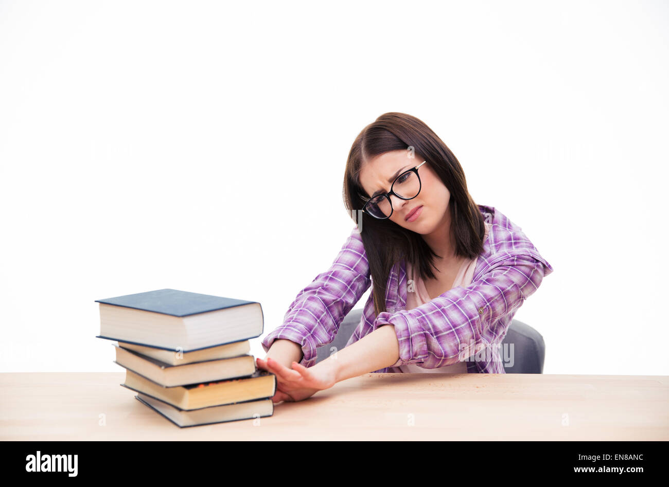 Young female student sitting at the table and push out books over white ...