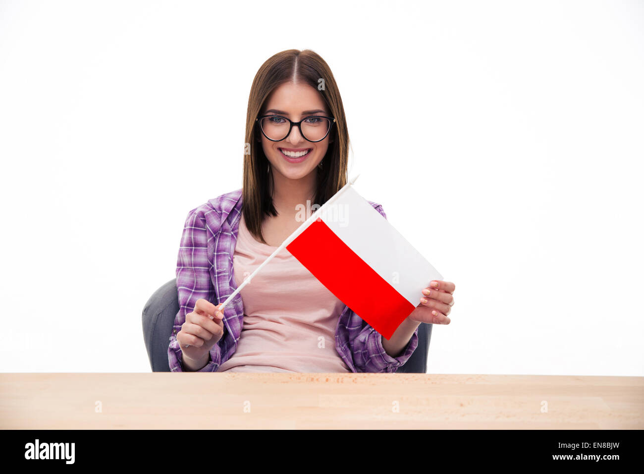 Young woman sitting at the table and holding Polish flag over white ...