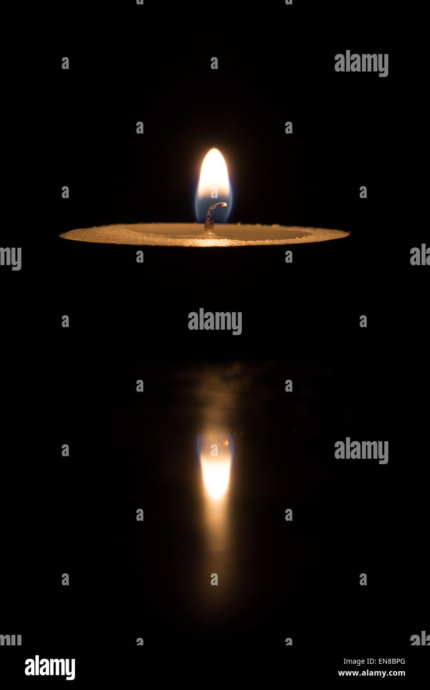 tea light candle and reflection against dark background Stock Photo - Alamy