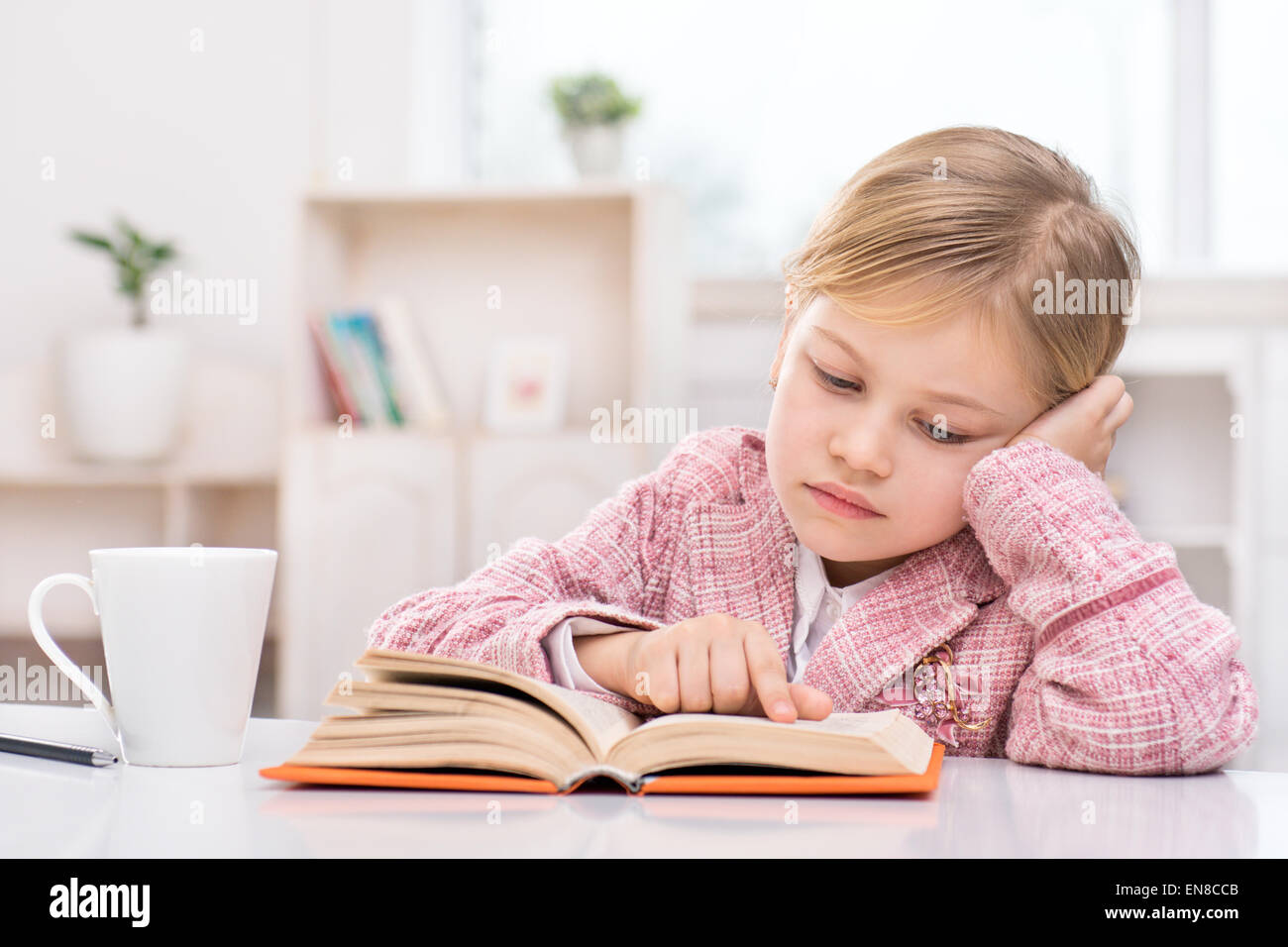 Little cute girl sadly reading book Stock Photo - Alamy