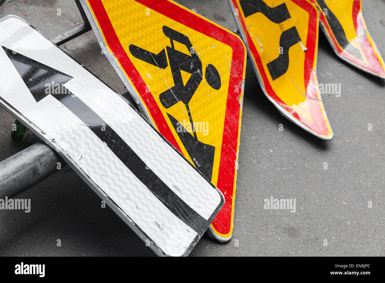 Bright red and yellow roadsigns lay on the asphalt road. Under ...