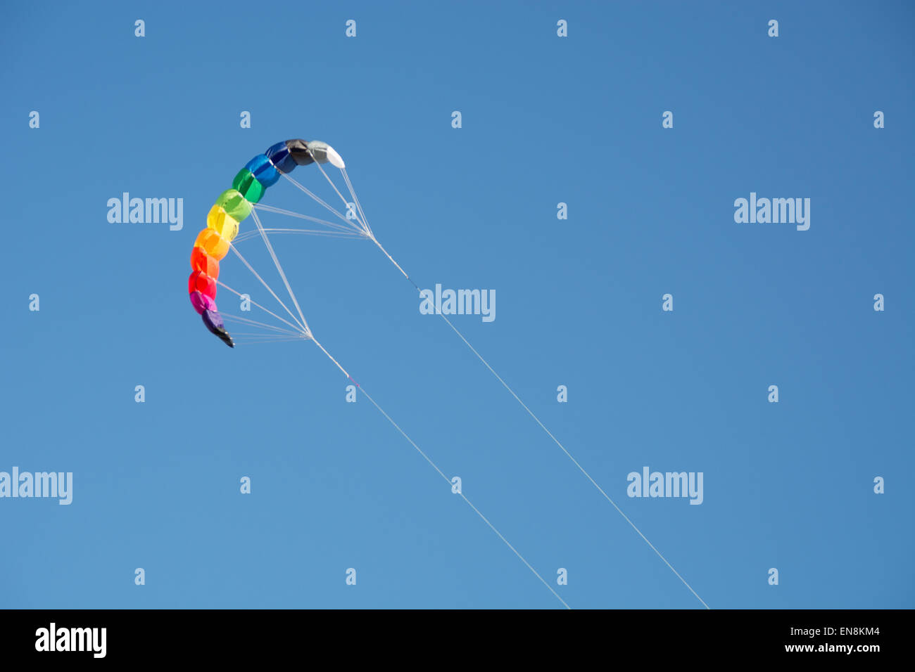 Colourful stripped kite flying high in the blue sky with visible ...