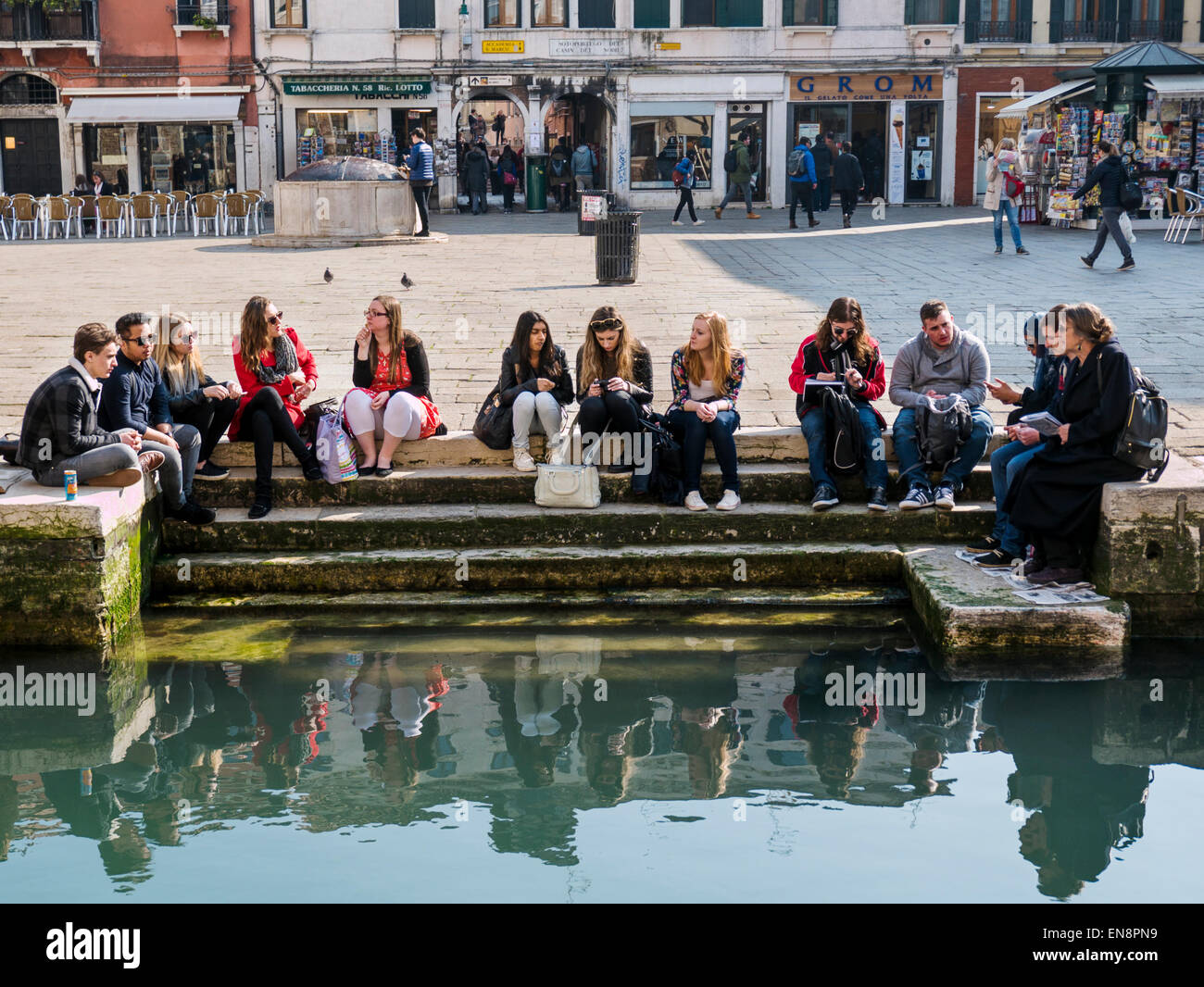 Students sitting along canal enjoy Venice, Italy, the City of Canals ...