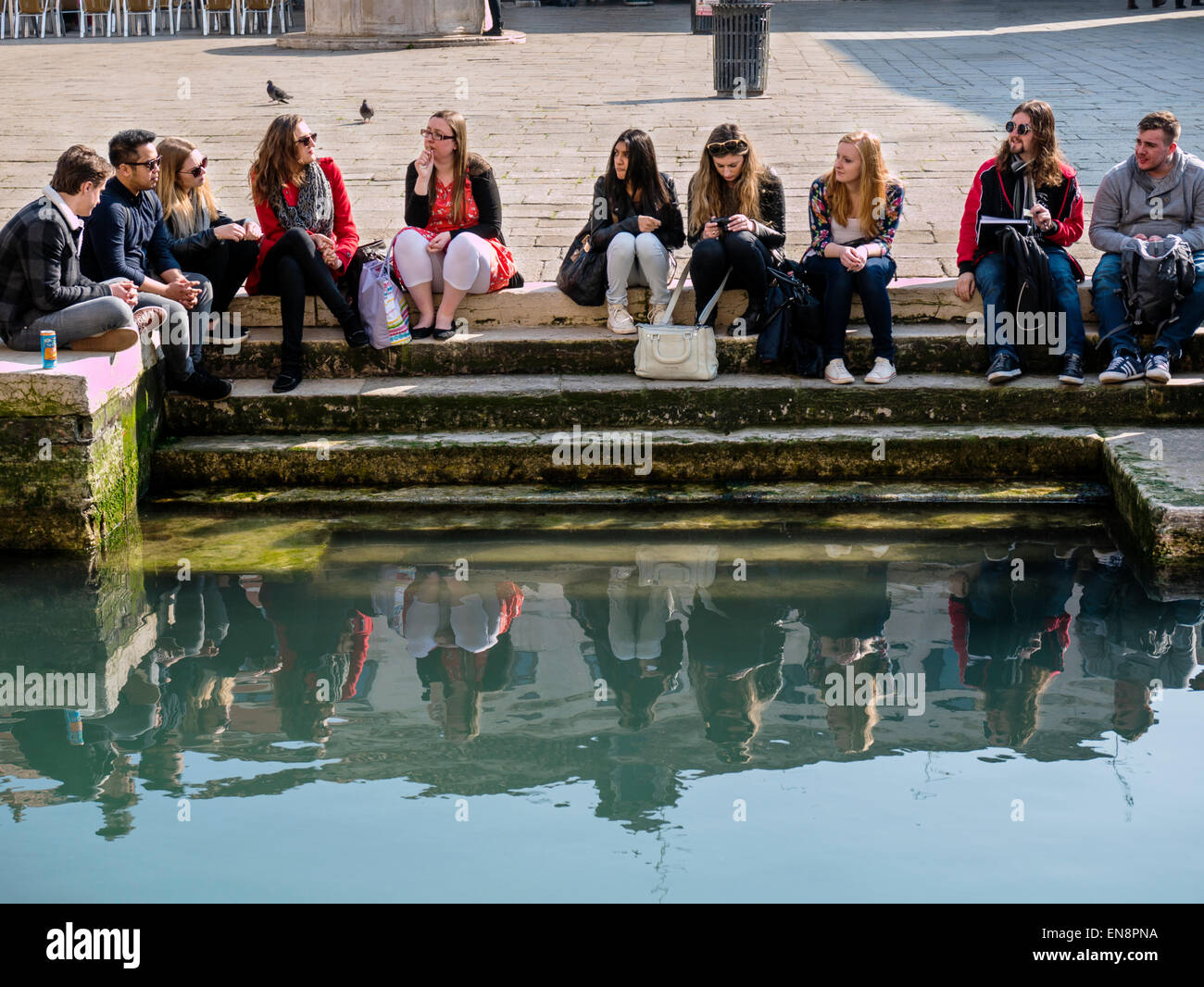 Students sitting along canal enjoy Venice, Italy, the City of Canals ...