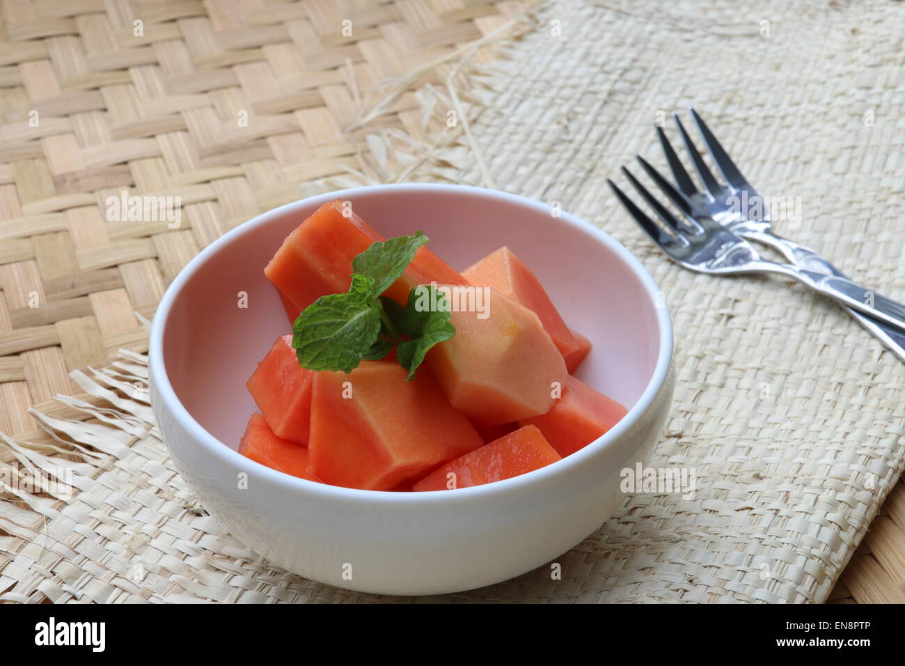 Papaya cubes in a white bowl, underlined with woven mat and tray Stock ...