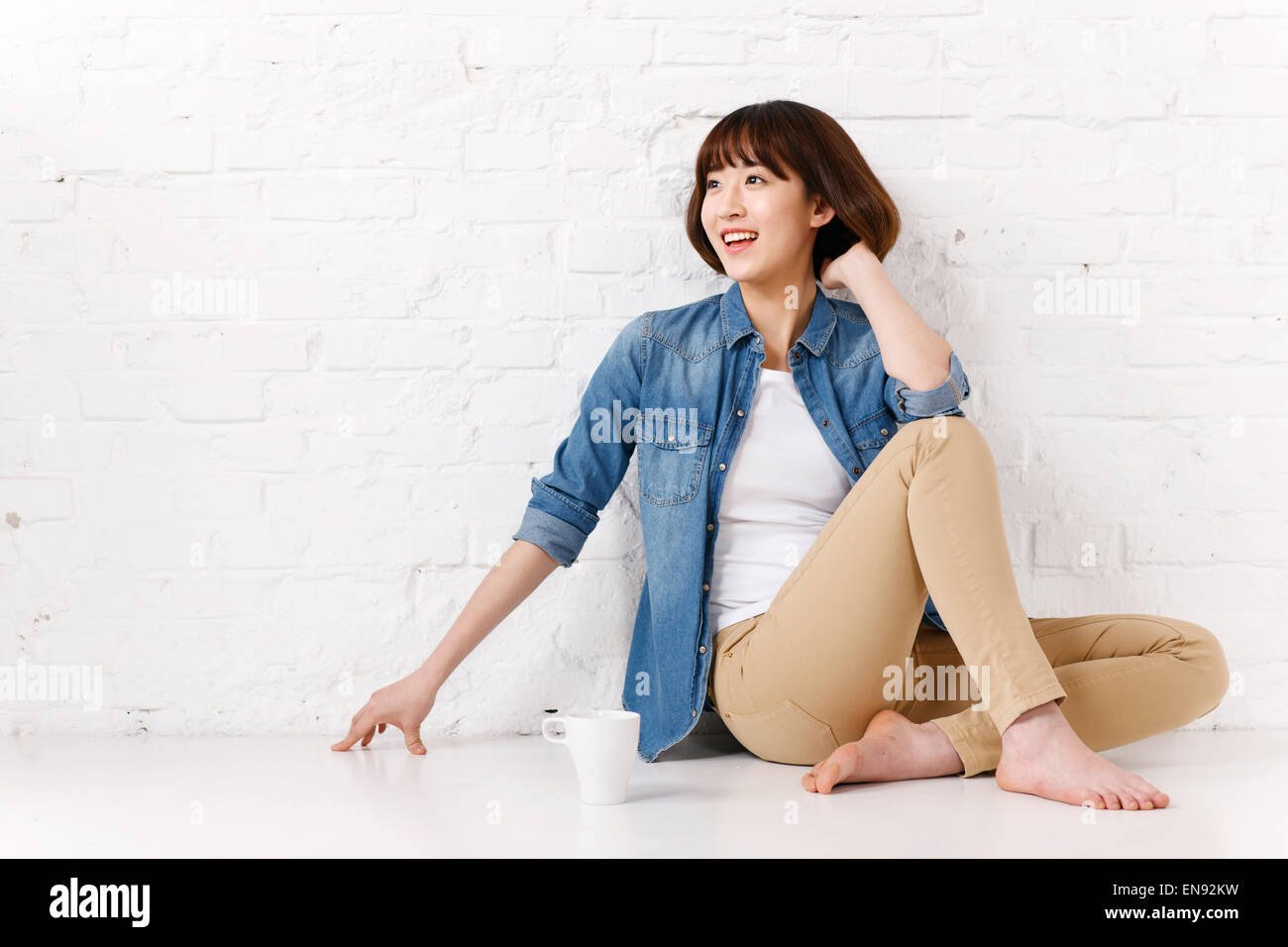 Elegant young woman sitting on the ground Stock Photo - Alamy