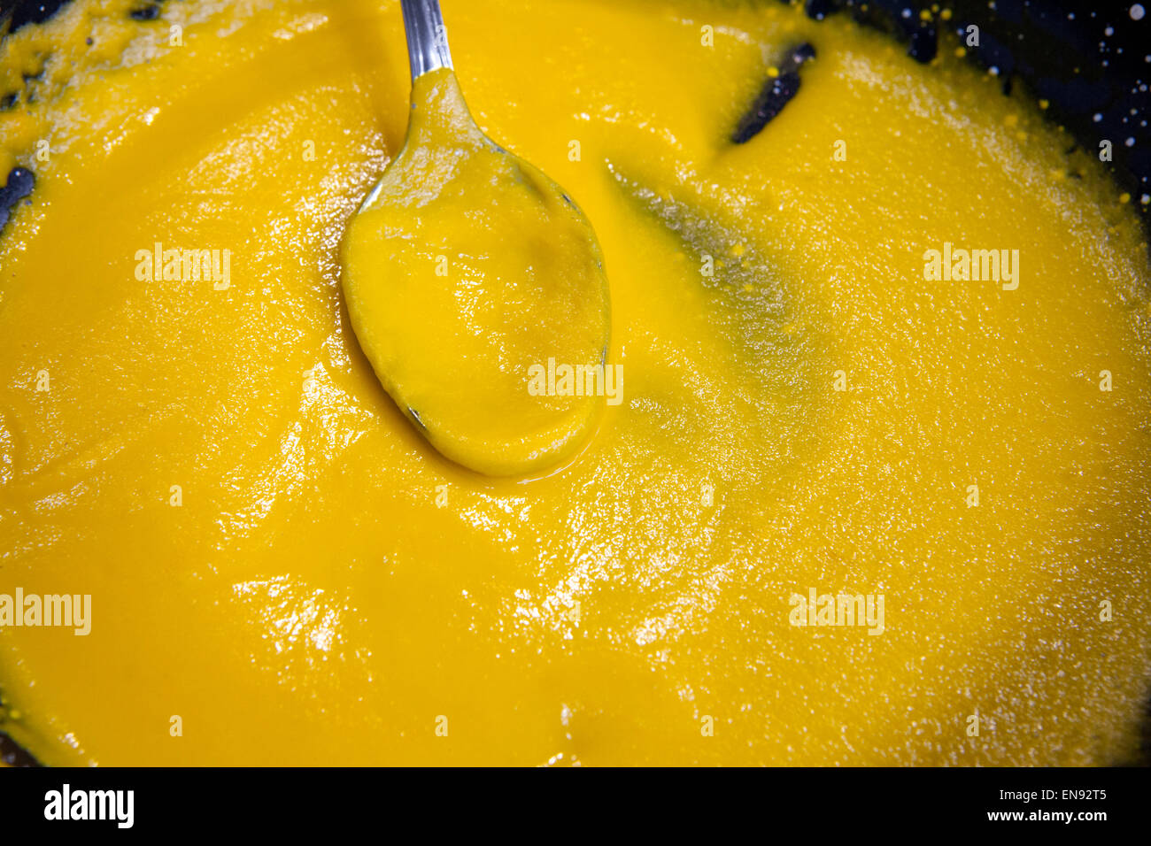 Heating yellowish carrot puree in a black pan Stock Photo - Alamy
