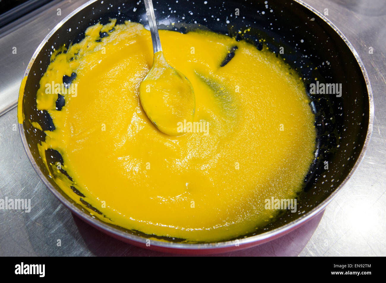 Heating yellowish carrot puree in a black pan Stock Photo - Alamy
