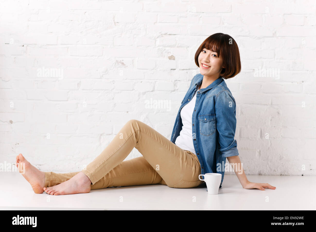 Elegant young woman sitting on the ground Stock Photo - Alamy
