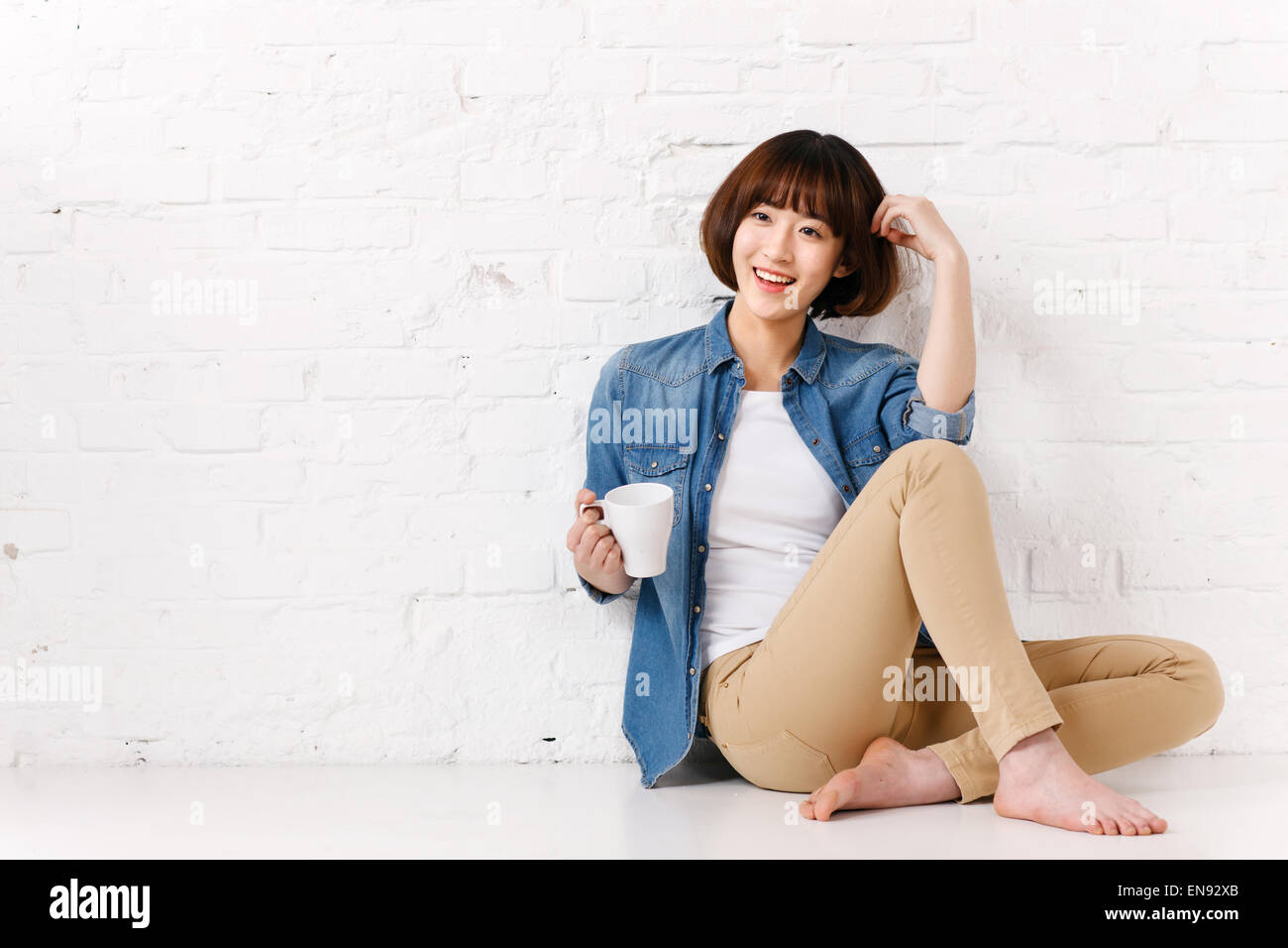 Elegant young woman sitting on the ground Stock Photo - Alamy