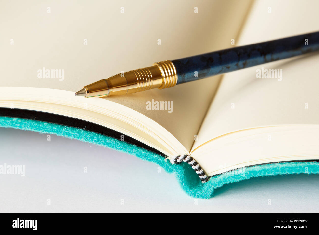 Open blank notebook with a pen on the note book page on a plain surface ...