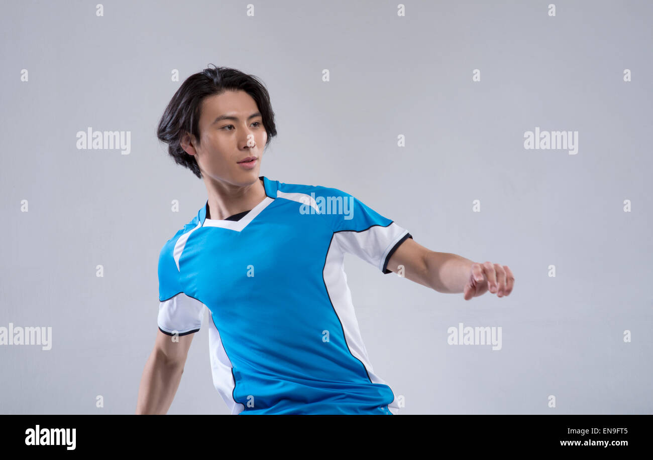 Young man kicking football Stock Photo - Alamy