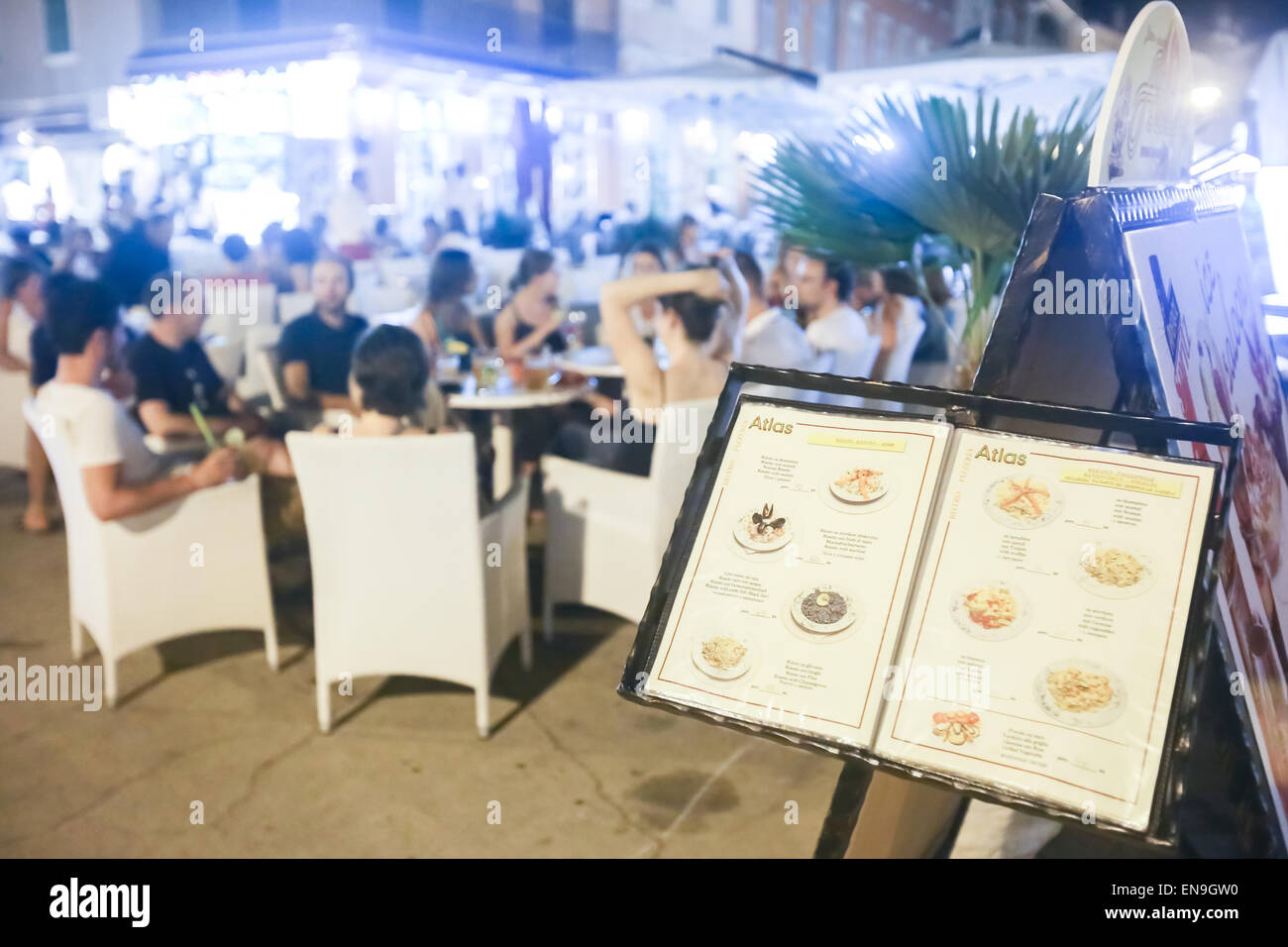 A restaurant menu displayed on a stand with people sitting in a ...