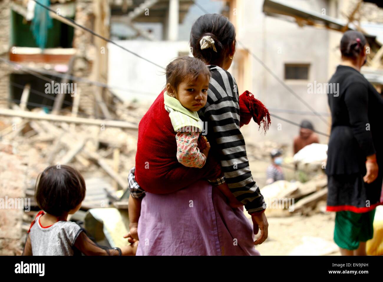 Sankhu, Nepal. 30th Apr, 2015. A woman carrying her child walks past ...