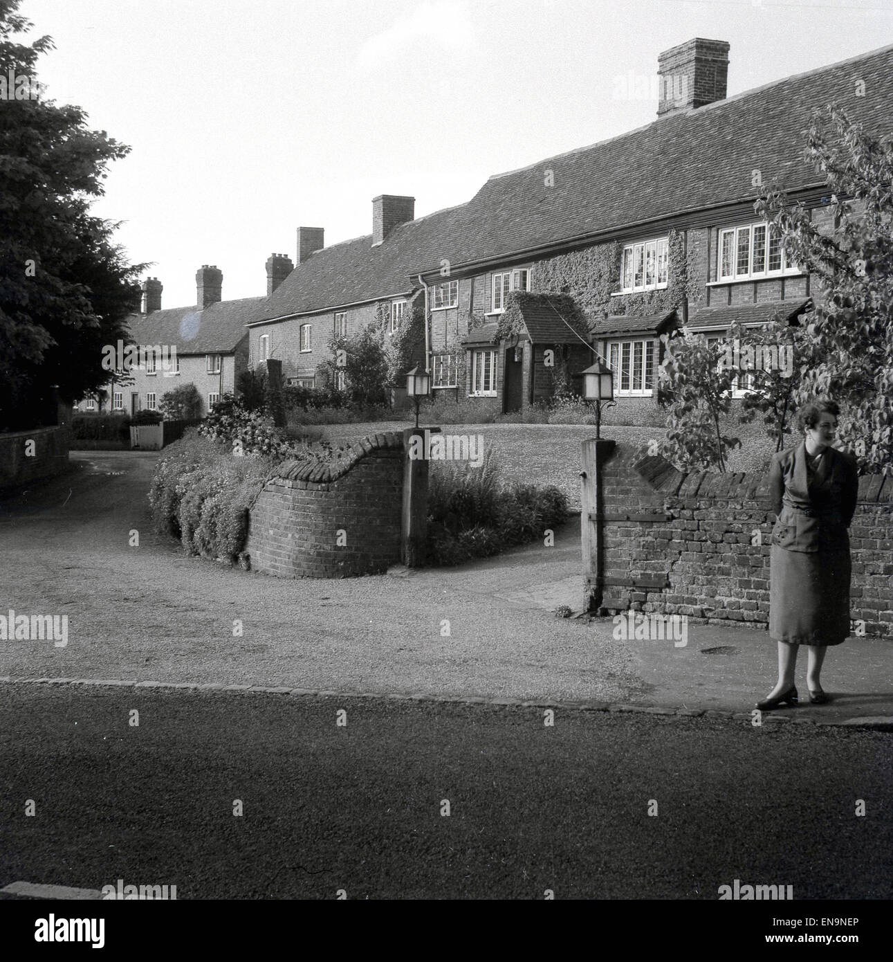 1950s, historical, england, lady standing outside a row cottages beside ...
