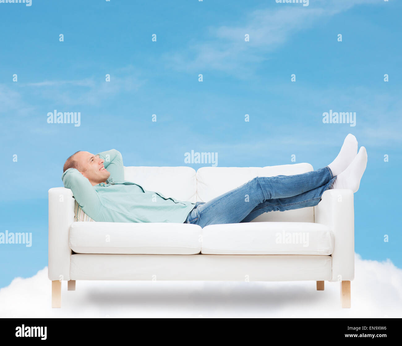 smiling man lying on sofa Stock Photo - Alamy