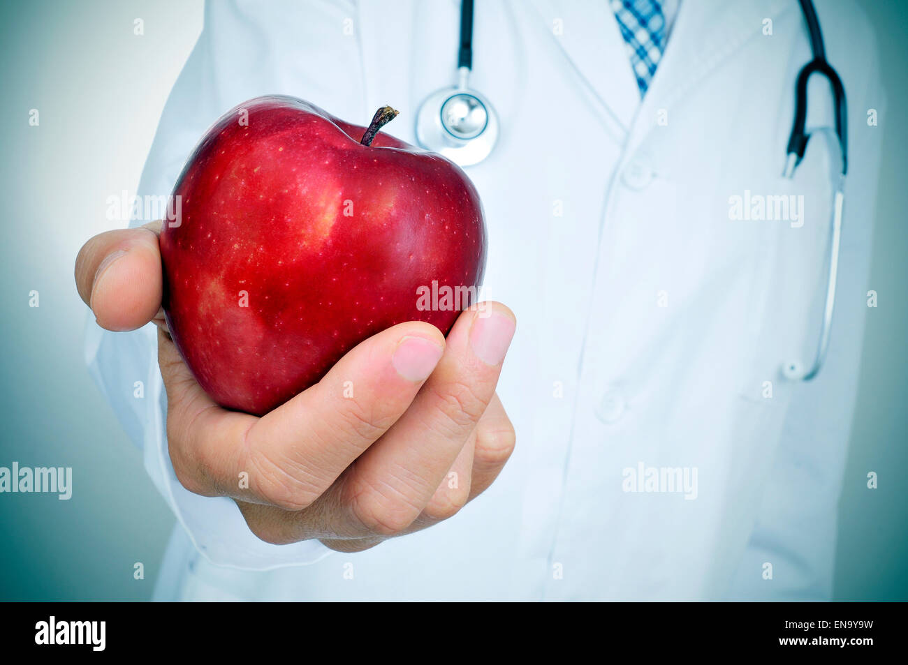 closeup of a young caucasian doctor with a red apple in his hand ...