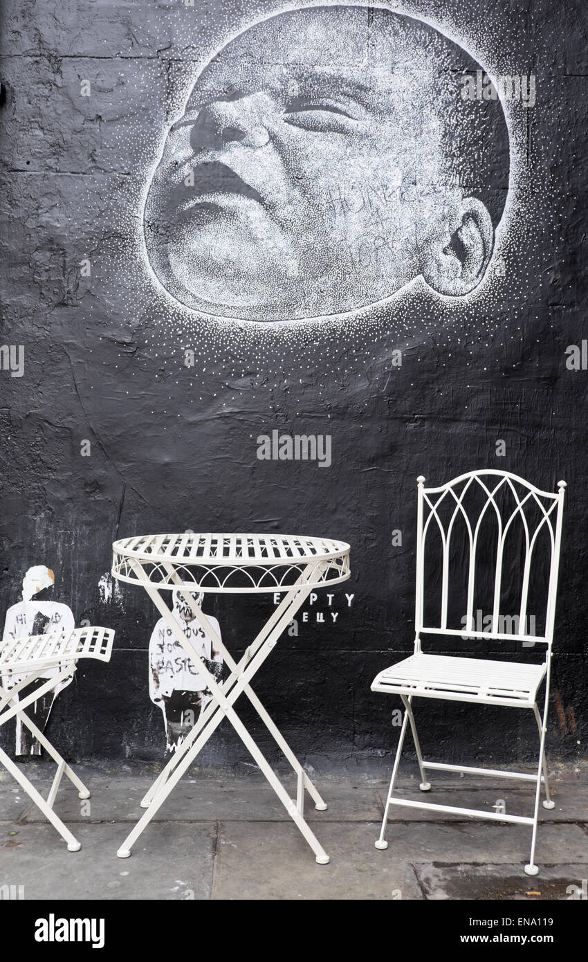Street art graffiti black & white with table and chairs in foreground ...
