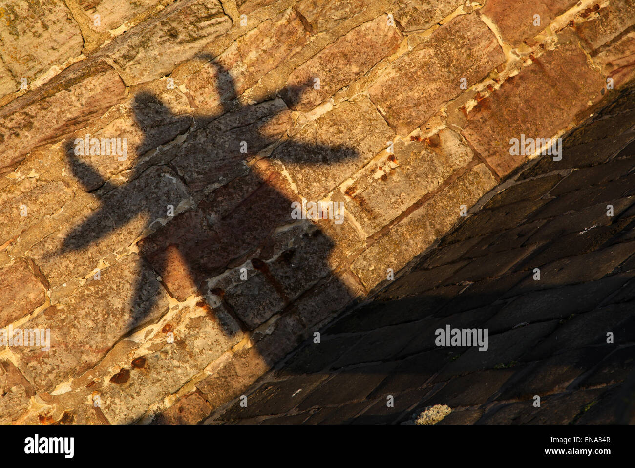 Brick wall sun light cast the shadows over it, three people lined up to ...